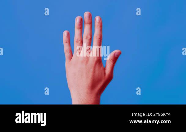 A hand is lifted in a gesture, showcasing fingers against a bright blue ...