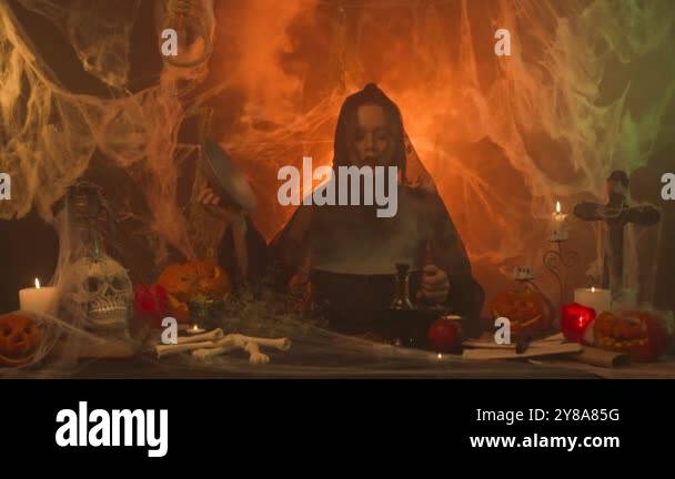 Witch in black clothing conjures up smoking cauldron in scary kitchen ...