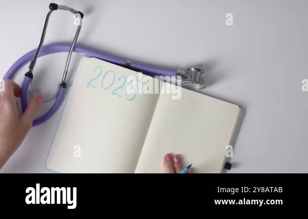 Female doctor writing in notebook goals for 2025 written on page lying ...