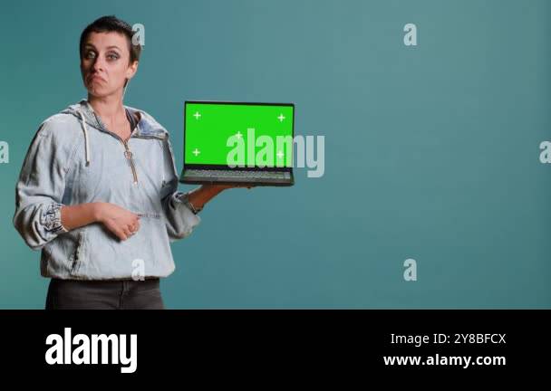 Young adult pointing at laptop with isolated chroma key screen in ...