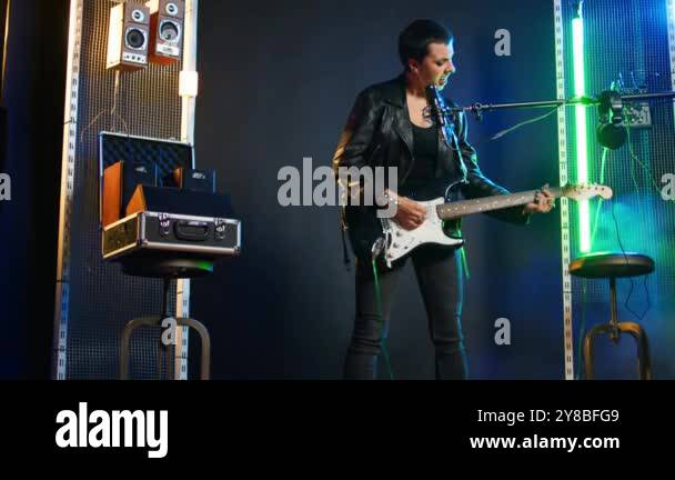 Confident female rocker performing live with a bass guitar on stage ...