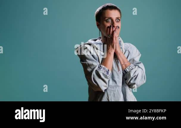 Scared nervous woman covering her mouth in shock against blue ...