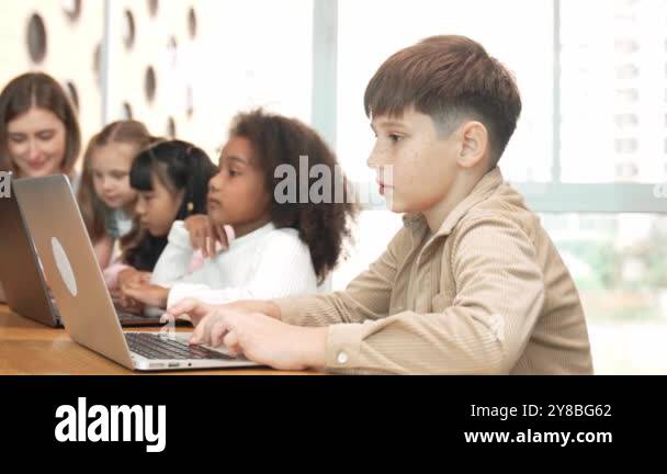 Boy playing laptop with multicultural friend learning prompt at STEM technology class ...