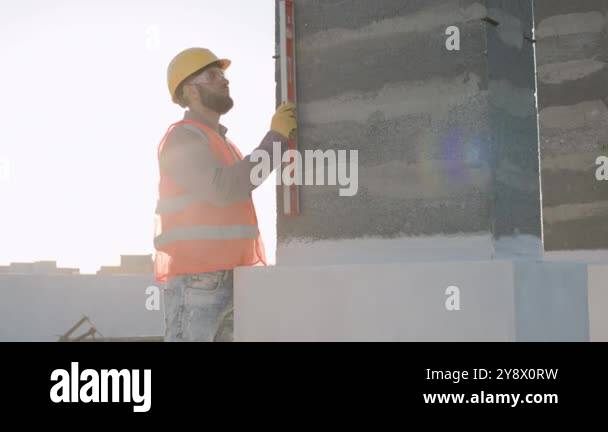 Construction worker using a level tool to ensure wall alignment at a ...