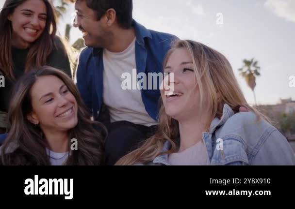 Diverse group of joyful young friends enjoying leisure time laughing ...