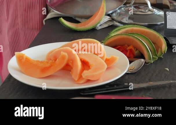 Slices of fresh melon arranged on a white plate on the kitchen counter ...