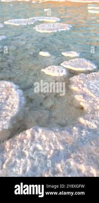 White salt deposits dissolve into turquoise water sunlight reflects off ...