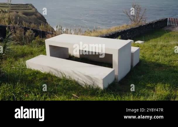 Concrete picnic table and benches on a grassy cliff overlooking the ...