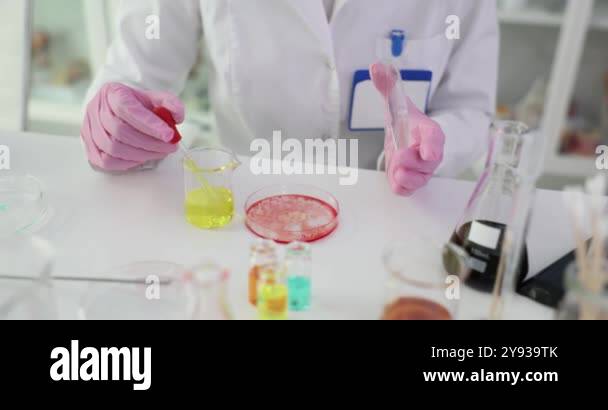 Chemist in pink gloves uses pipette to add chemical liquid reagent to ...