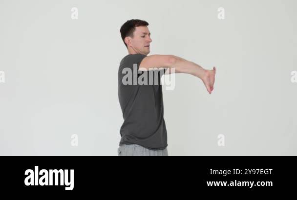 Concentrated man performs arm stretches on white background. Sportsman ...
