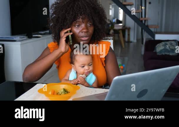 A cheerful Black African mother engages in multitasking, talking on the ...