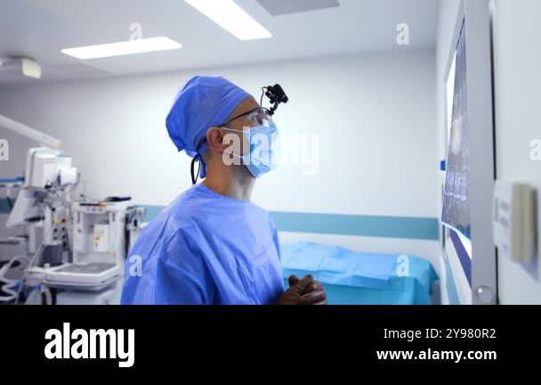 Neurosurgeon equipped with surgical loupes looks focused on the MRI ...