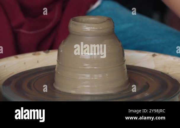 Close up shiny from water clay formed in shape of crooked vessel ...