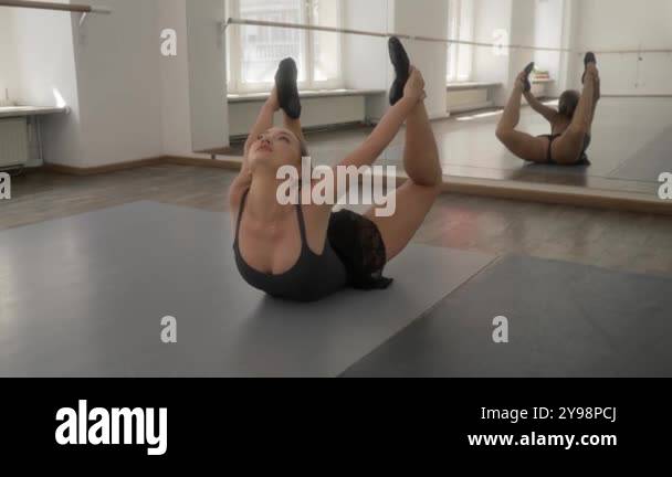 Ballerina performs the Bow Pose (Dhanurasana), stretching her front leg muscles, chest, and ...