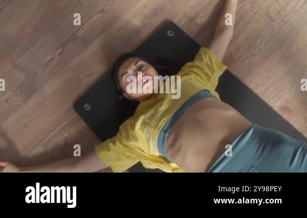 Woman lying on her back performing a glute bridge exercise, lifting and ...