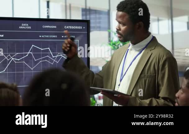 Coworkers engaging in a problem solving meeting at a corporation, using an interactive board to ...