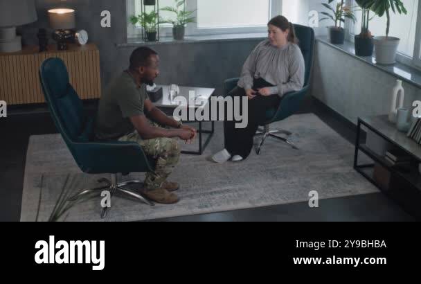 High angle of African American military man with PTSD sitting in chair ...