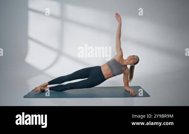 Fitness woman training body core muscles doing side plank on workout. Concentrated woman in ...