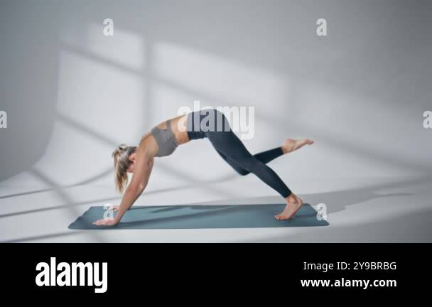 Flexible woman making downward facing dog pose practicing yoga on ...