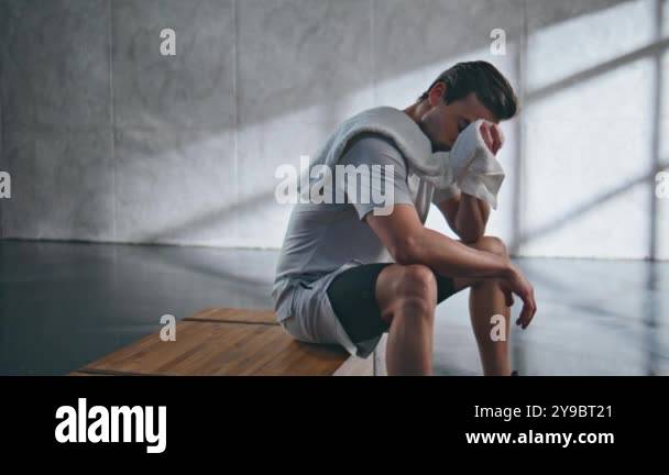 Sweaty athlete wiping face using towel at loft location. Professional ...