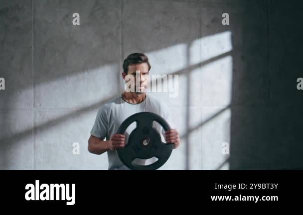 Motivated athlete lifting weight plate in sport gym club closeup ...