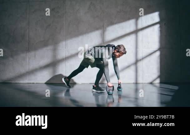 Strong model holding weights equipment standing plank at grey wall ...
