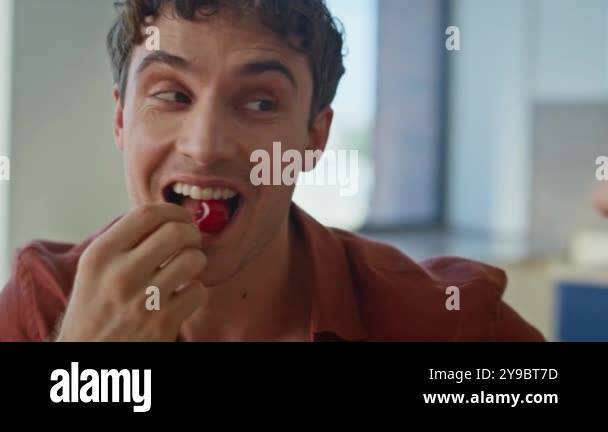 Joyful man eating cherry with happy expression spending time with ...