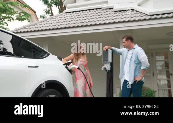 Happy and lovely couple with eco-friendly conscious recharging electric ...