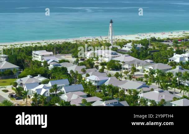 Expensive waterfront houses and white Boca Grande lighthouse on ocean shore. Small town on ...