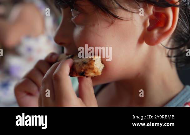 Young boy holding a piece of pizza crust near his mouth, looking ...