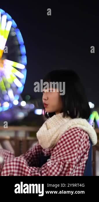 A young Taiwanese woman in her 20s is walking at night while on a date at an amusement park in ...