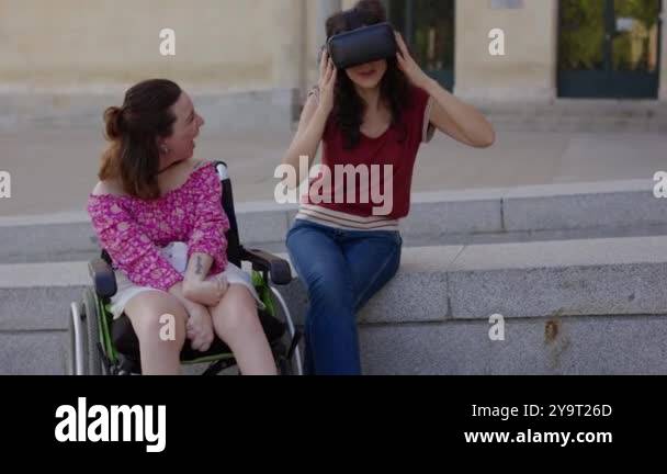 Woman with cerebral palsy in a wheelchair smiles as her friend uses a ...