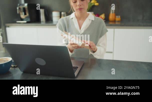 A young woman deeply engaged in reading a book while seated at a desk ...