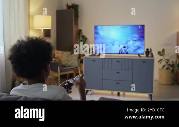 Back view of little Black male gamer playing shooter video game on ...