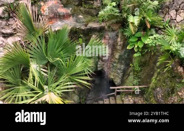 Water cascades over stone steps into a serene pool at the bottom of a ...