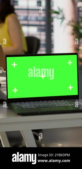 Vertical video Green screen laptop on desk in workspace with admins in ...