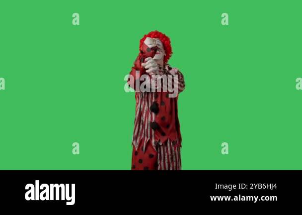 Funny clown on green screen chroma key. Actor man in red wig and suit ...