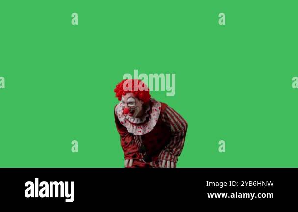 A funny clown on a green screen chroma key. Actor man in red wig and ...