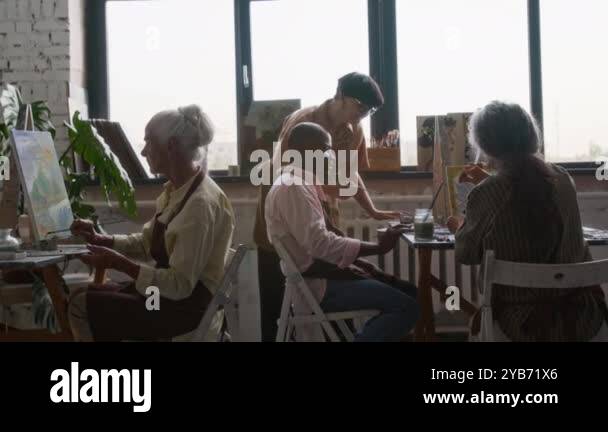 Female teacher helping senior man finish his picture, two women ...