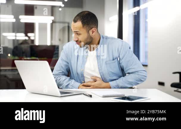 Upset african american businessman feels stomach pain while working on ...