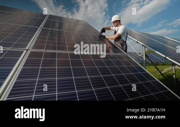 Engineer installs solar panels with precision using a power drill. Captured outdoors, this image ...