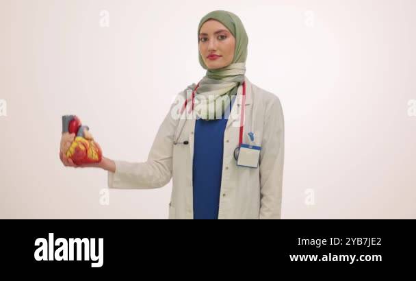 Woman doctor in hijab wearing uniform shows heart model. Muslim ...