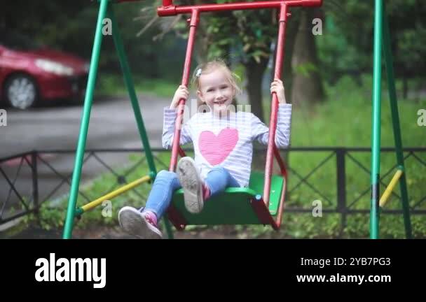 Happy 6 years old girl on a swing. Happy kid on playground swinging on ...