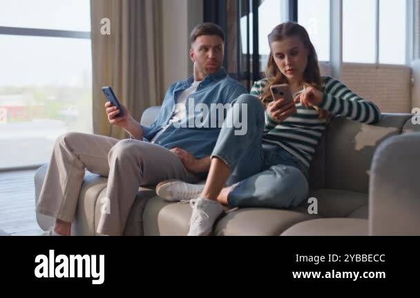 Offended couple browsing smartphones at domestic weekend. Sad boyfriend ...