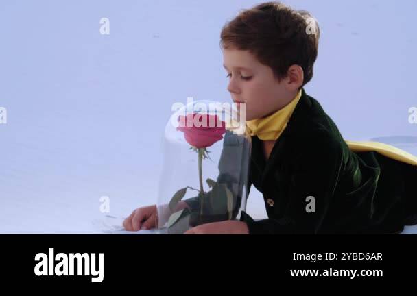 A young boy dressed as the Little Prince lays on a white desert surface ...