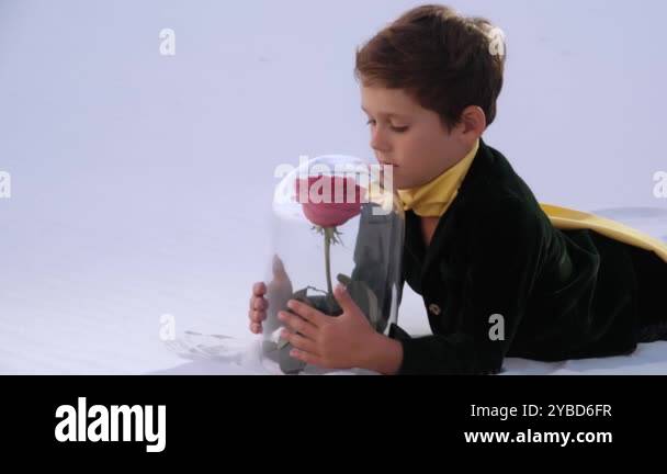 A child dressed as the Little Prince lays on the desert floor, gazing ...