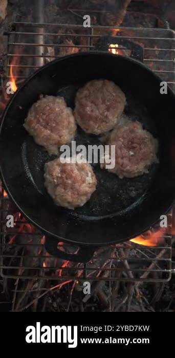 Vertical footage of four burger patties fried on hot pan in nature ...