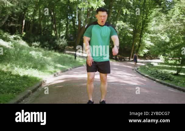 Asian runner athlete with knee pain in park. Japanese man massaging ...