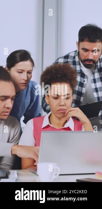 Vertical screen: Diverse team reacts to bad news while gathered around ...