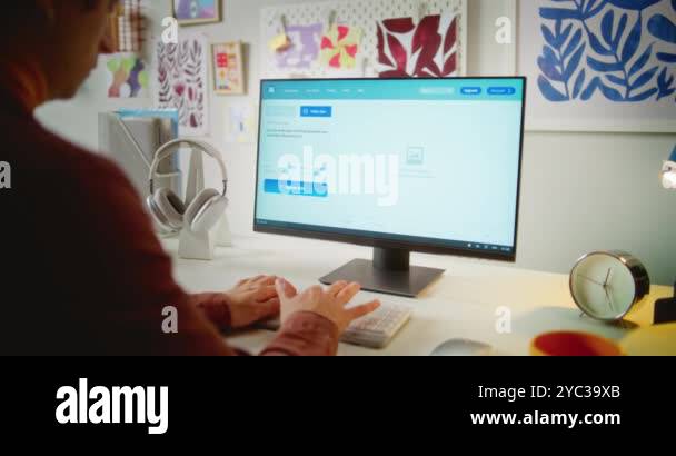 Back view of young man typing prompt in AI video generator on PC ...